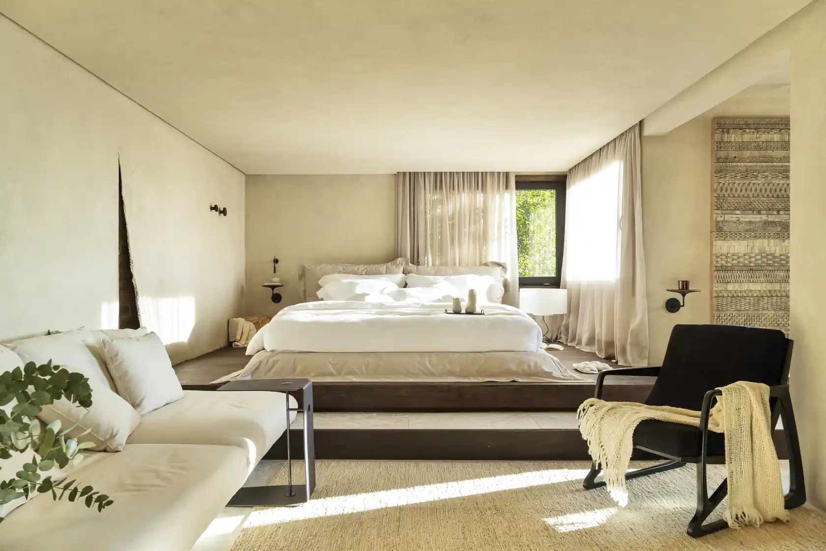 Com rasgo na parede, suíte interliga sofá, cama e banheira com tablado